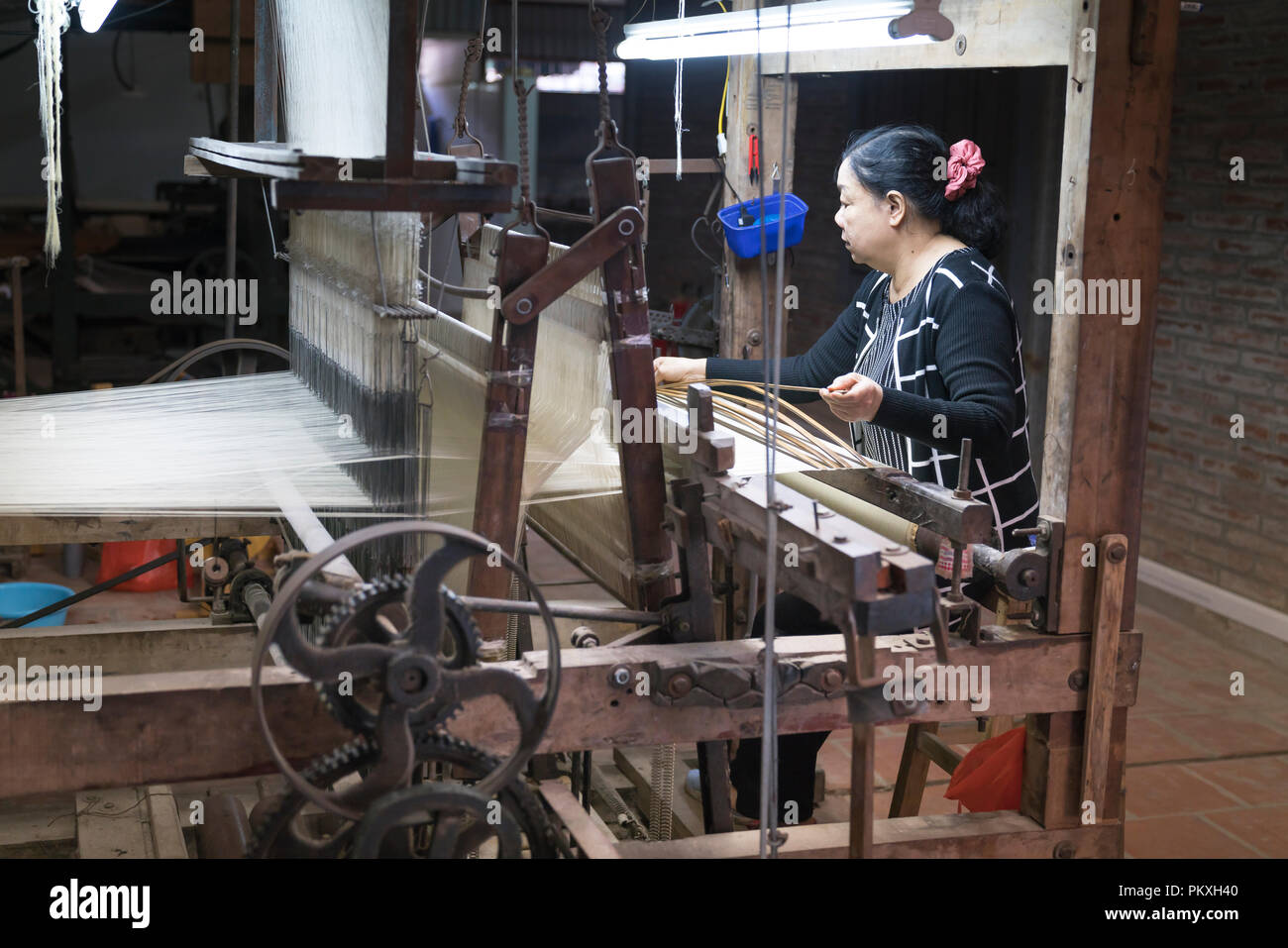 Vietnamese woman operates a silk weaving machine in the silk factory in ...