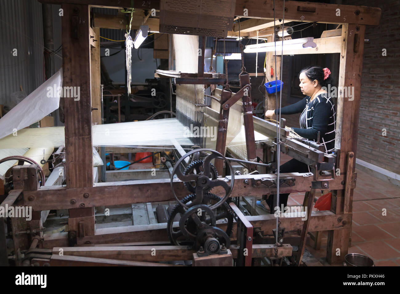 Vietnamese woman operates a silk weaving machine in the silk factory in ...