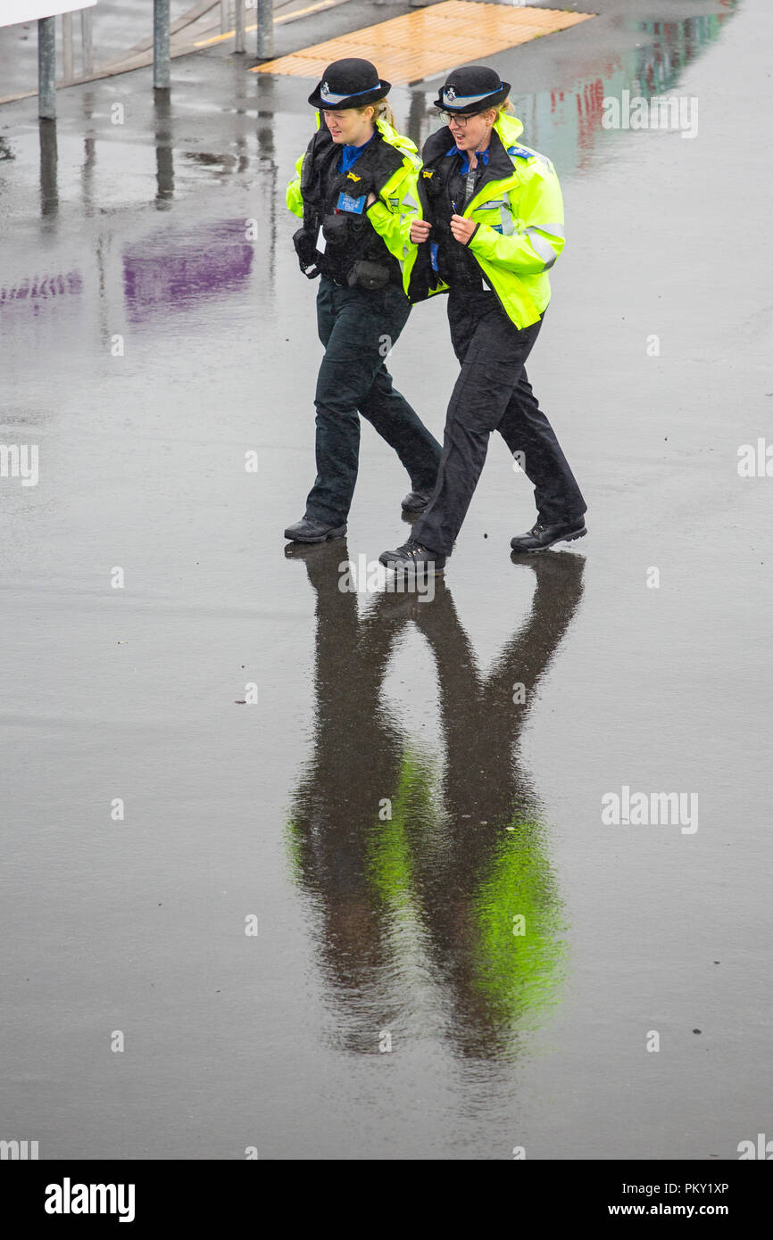 Two police officers walking in the rain with reflections in wet ...