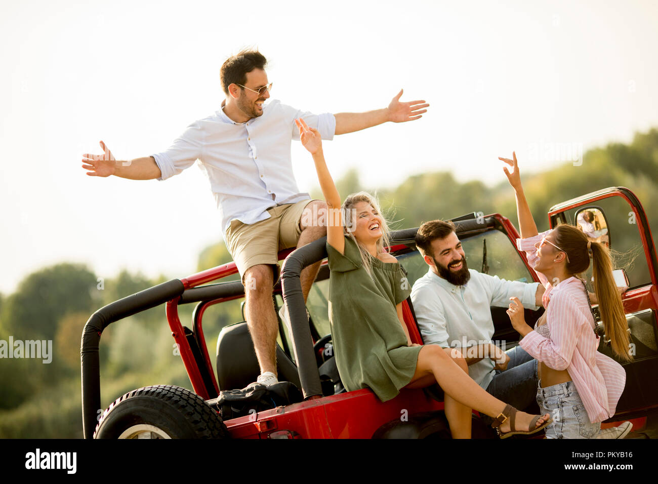 Happy friends having fun in convertible car at vacation by river Stock ...