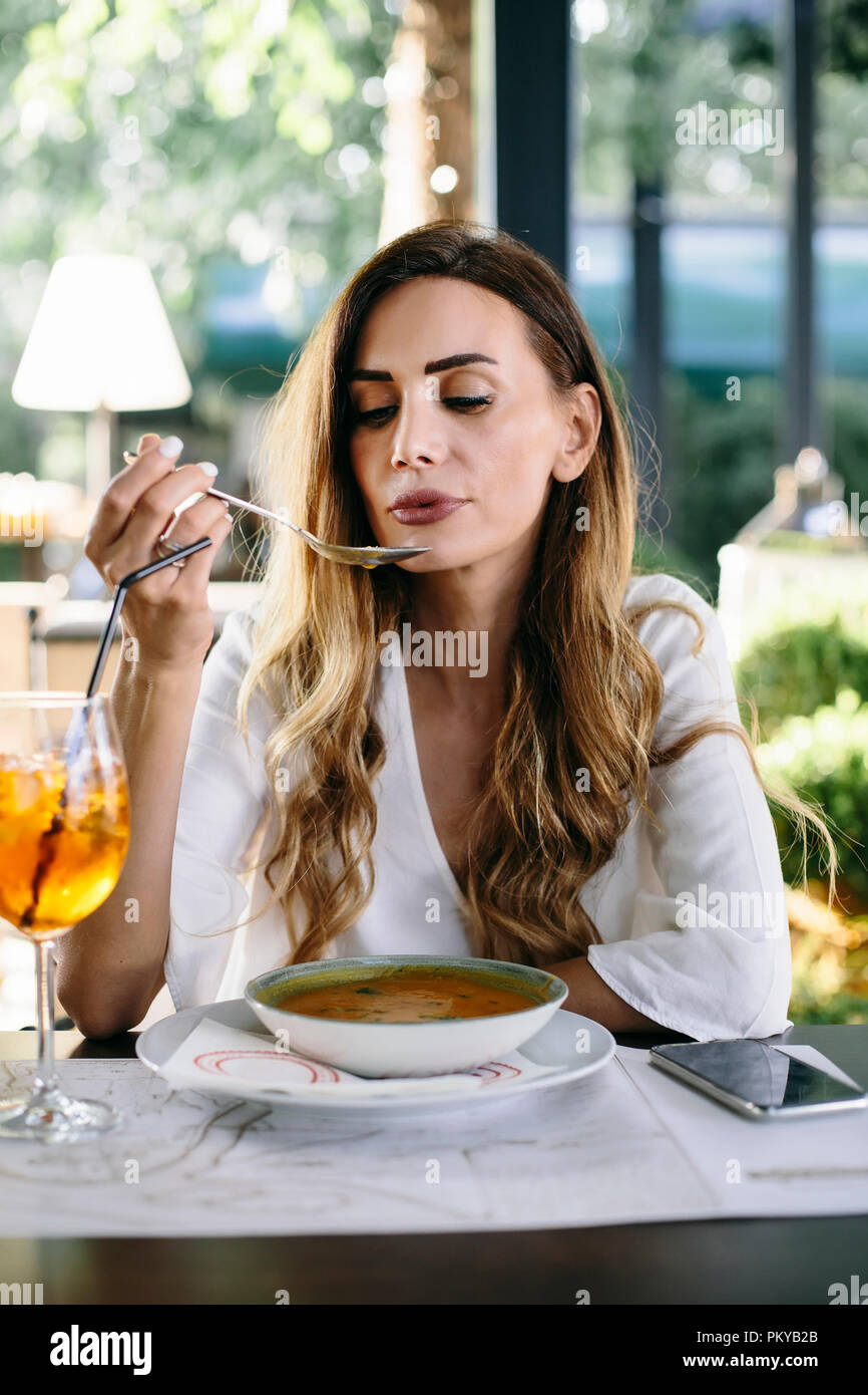 Young attractive woman eating soup in restaurant Stock Photo - Alamy