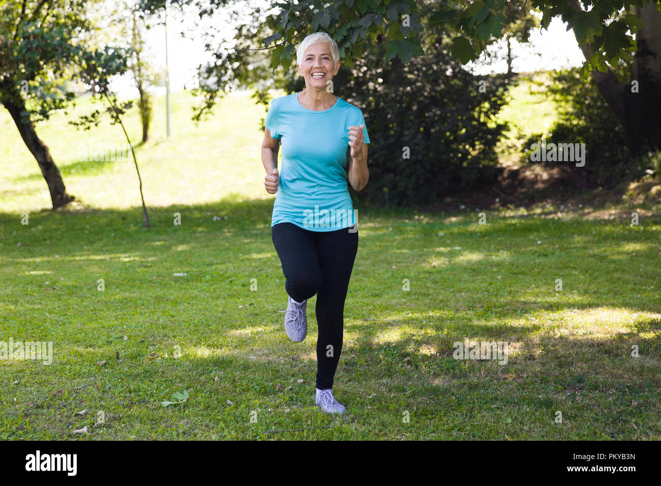 Front view of senior woman jogging through park Stock Photo - Alamy