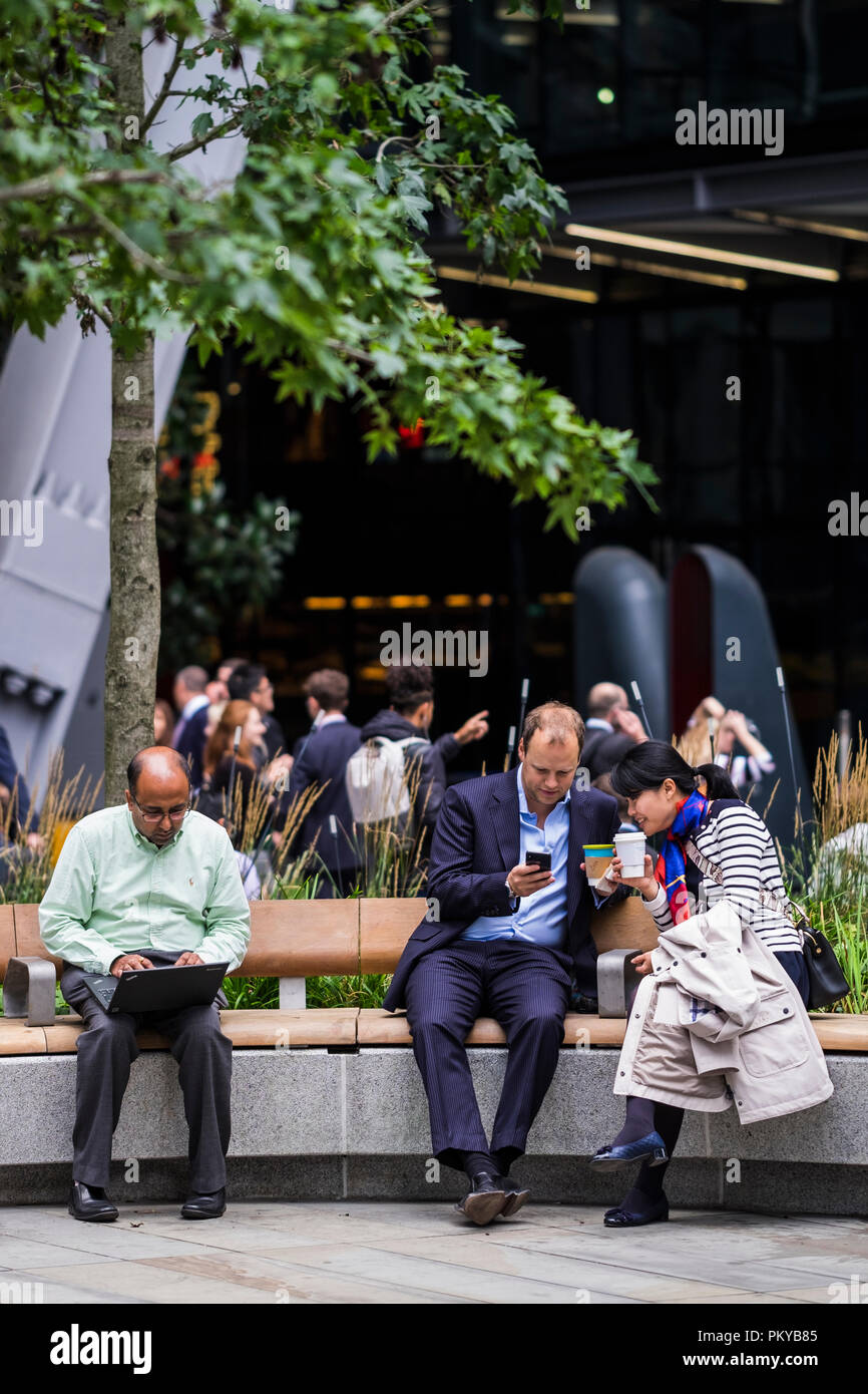 City of London workers using mobile technology at seat outside, London ...