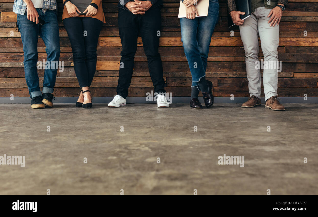 Group of people leaning against the wall before a job interview with ...