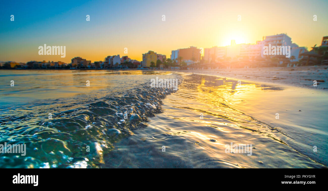 Wavy curves of sea is covered in golden sunset light. Sea at sunset ...