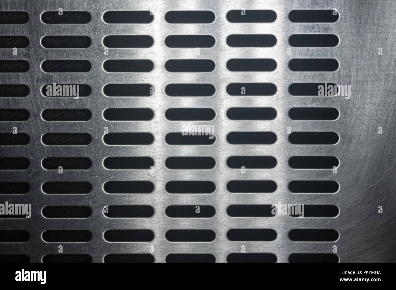 stainless steel grating with oblong holes on black background, close-up ...