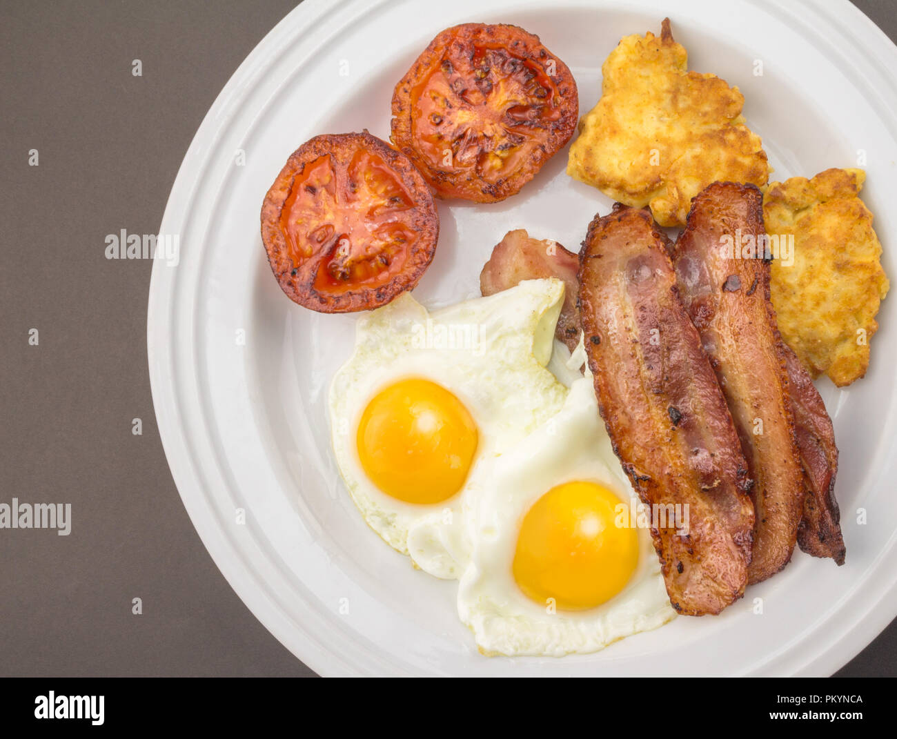 Bacon and egg breakfast with hash browns and fried tomato - Top view photo Stock Photo - Alamy