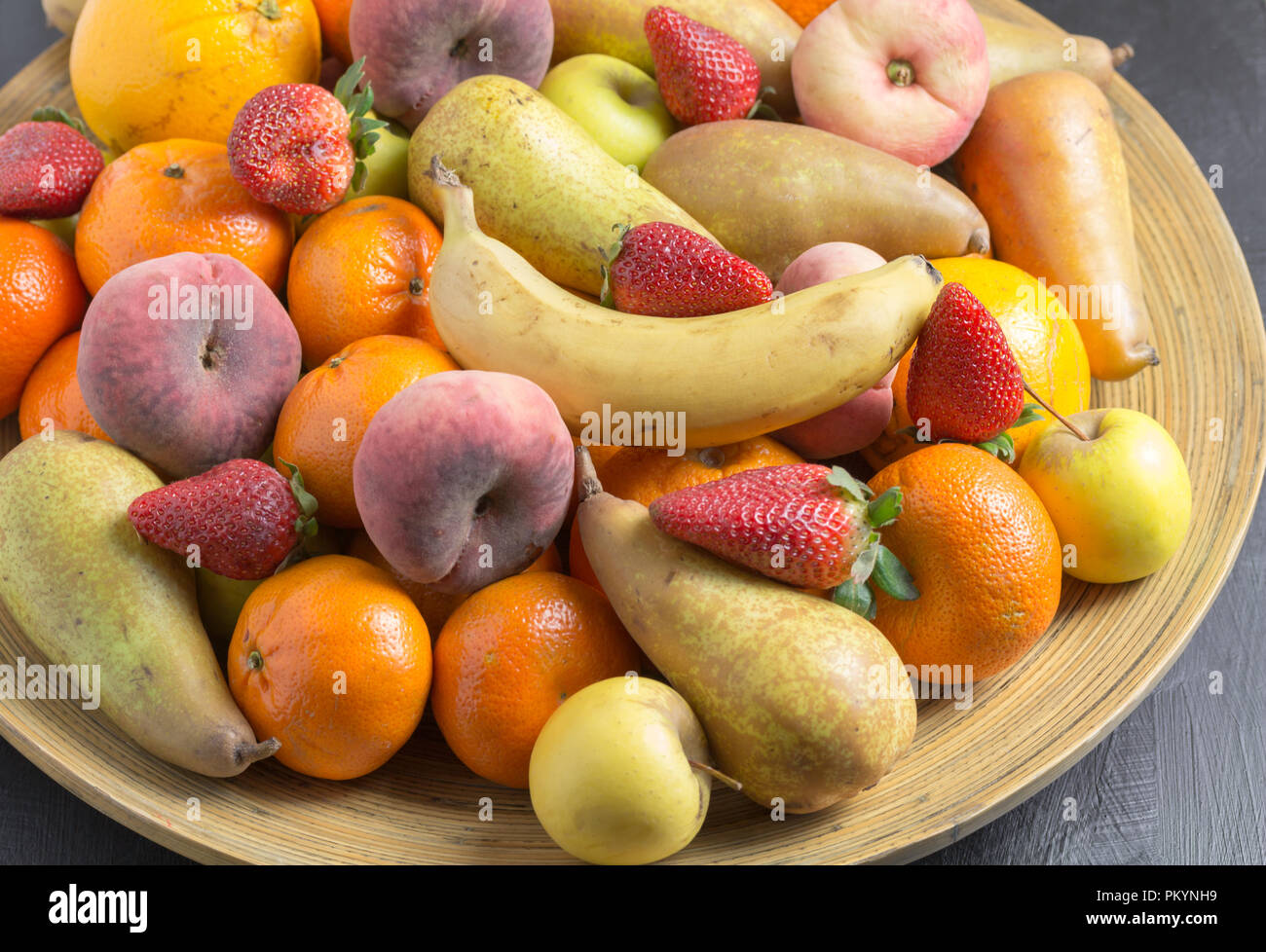 Fruit bowl with exotic whole fruits close up in rustic wooden bowl ...