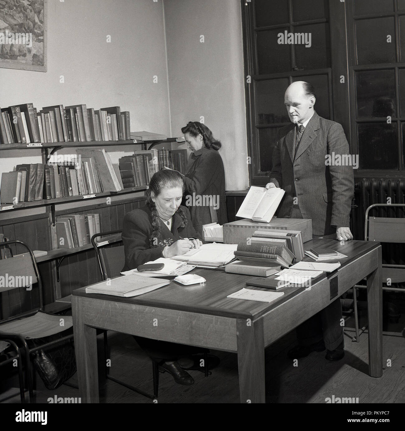 1950s, historical, a well-dressed gentleman in a library standing ...
