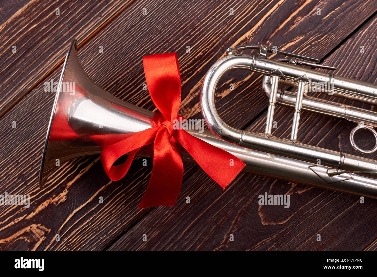 Trumpet with red bow. Shiny trumpet with red bow on brown wooden ...