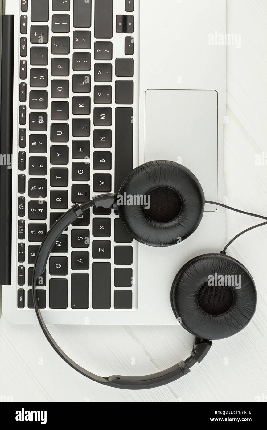 Black headphones on silver laptop. Headset on keyboard computer laptop ...