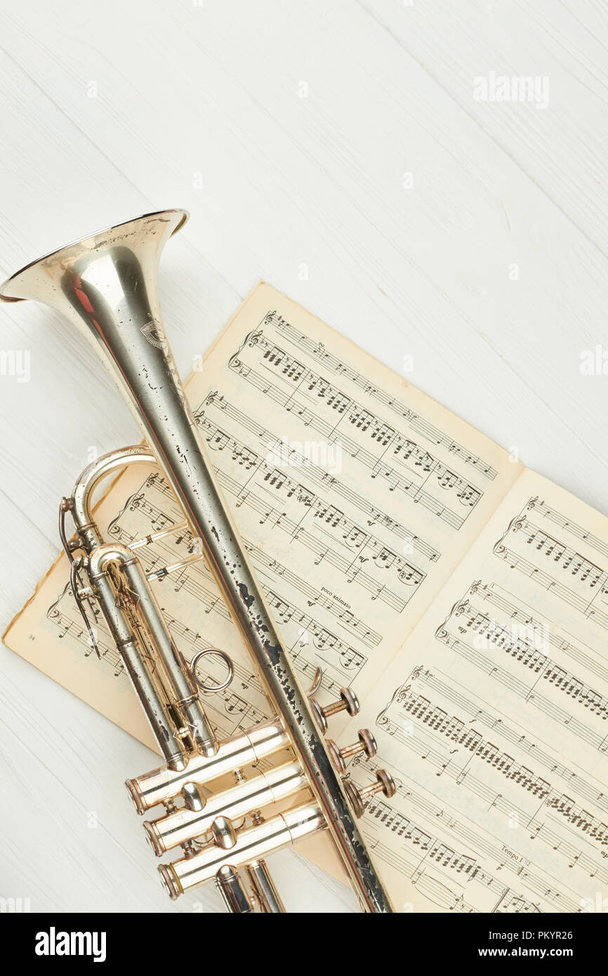 Rusty trumpet on musical notes, top view. Music notes book and trumpet ...