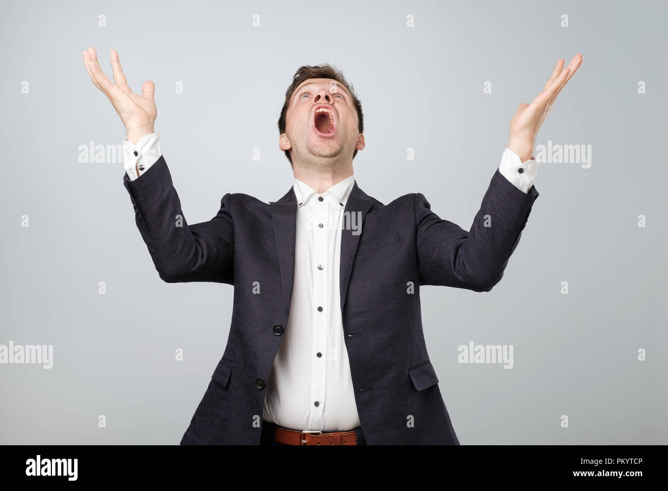 Portrait of excited young male in suit screaming in shock and amazement ...