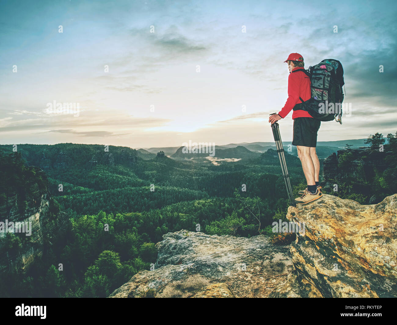 Tall photographer with heavy backpack and tripod in hands stand on ...