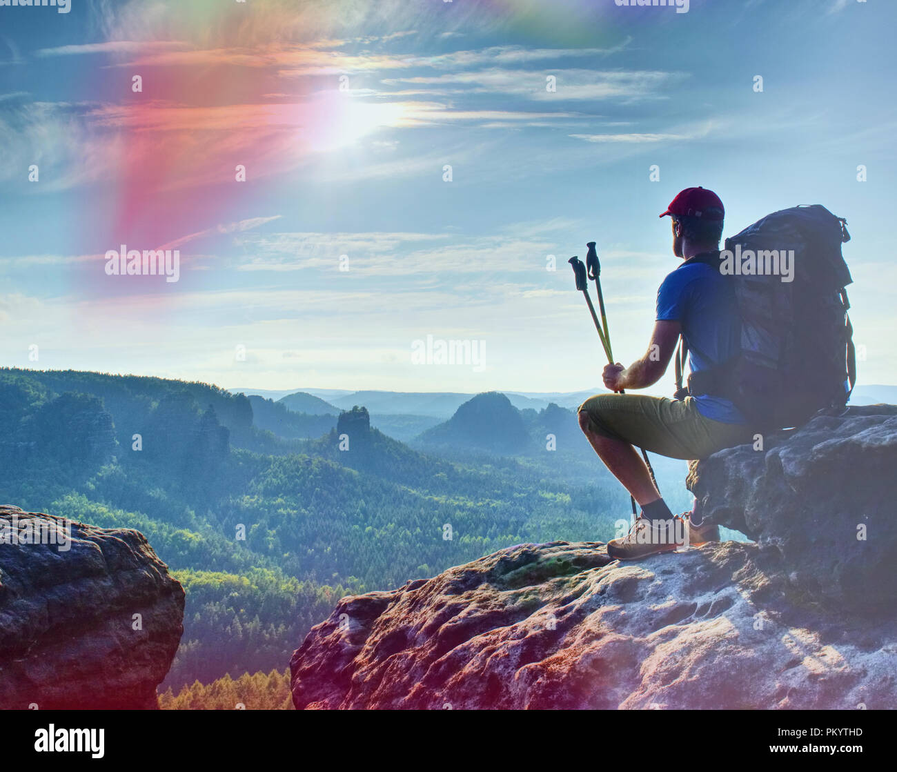 Man sitting on the rock cliff in mountain and watching on sunrise ...
