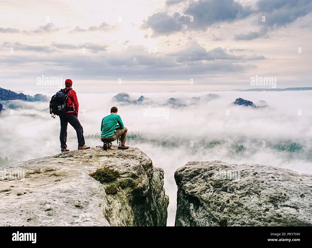 Hiker and photographer with camera stay on cliff and takes photos ...