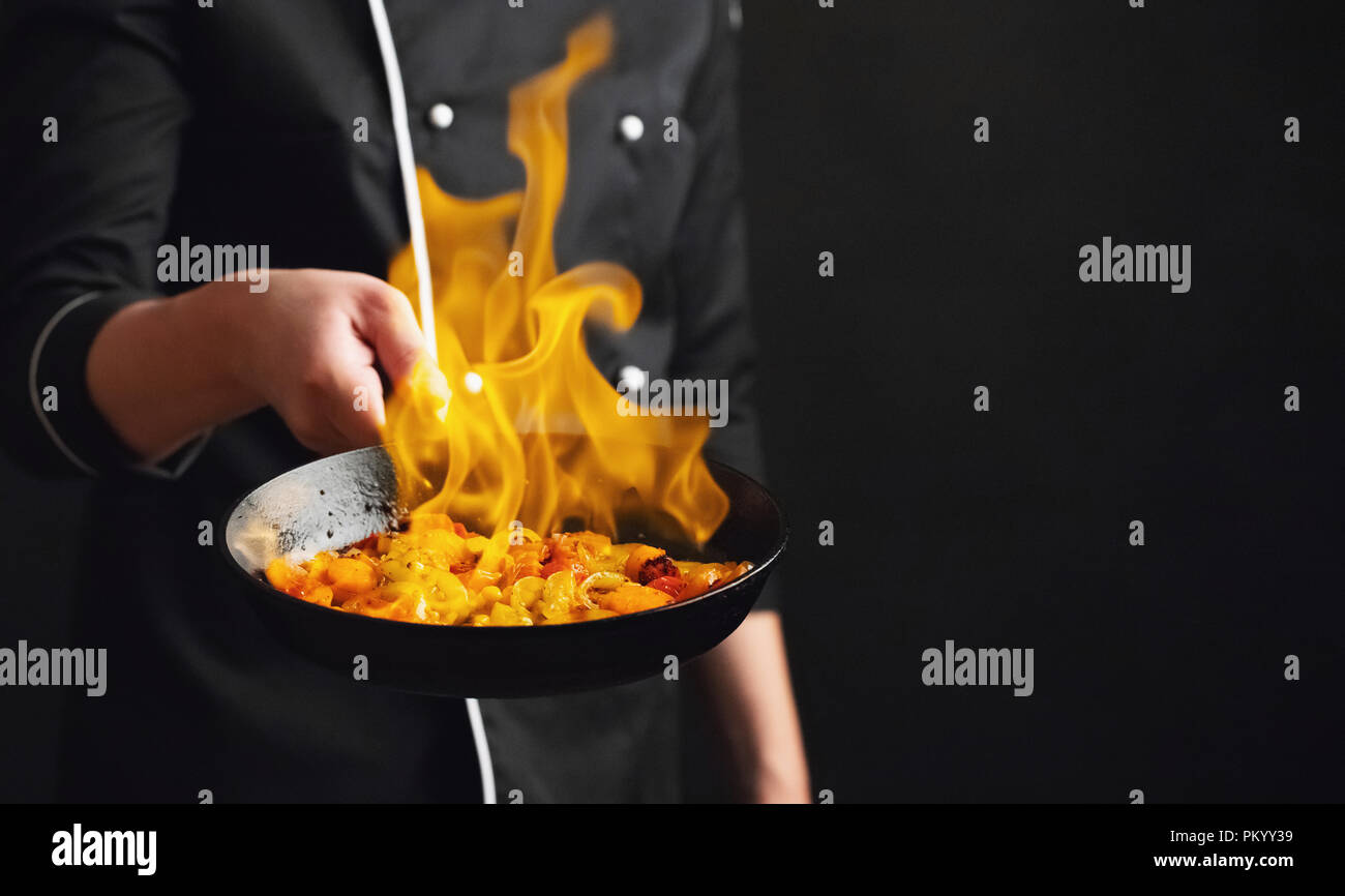 Professional chef and fire. Cooking vegetables and food over an open ...