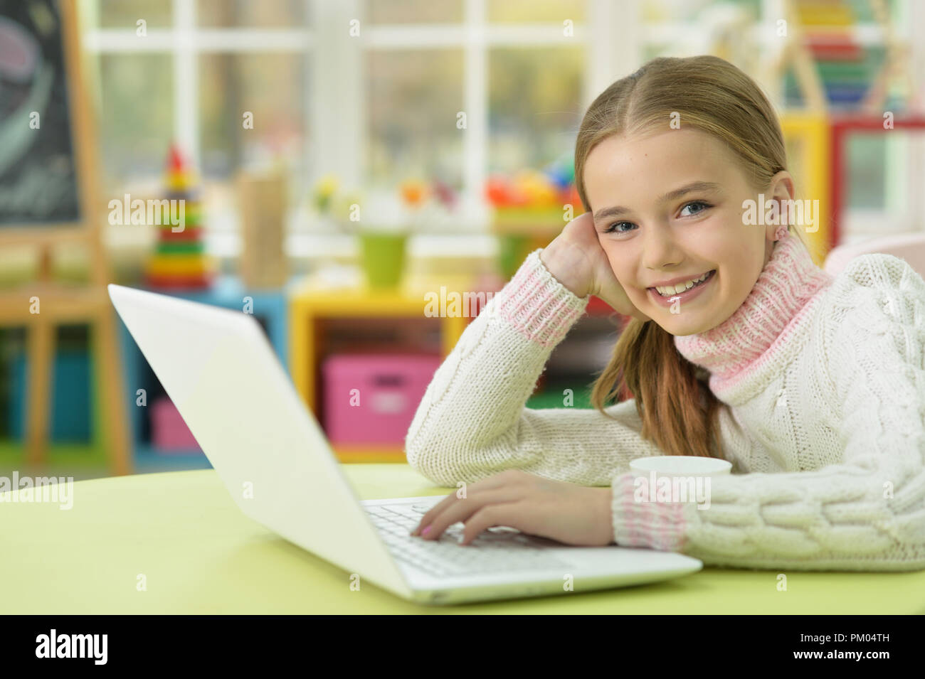 Portrait of little girl using laptop while sitting Stock Photo - Alamy