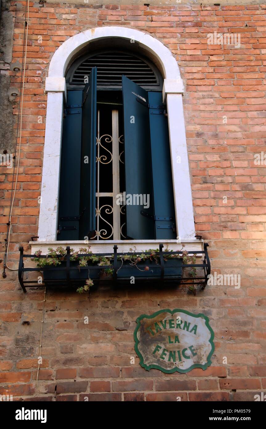 Arched window with shutters and street name in Venice Stock Photo - Alamy
