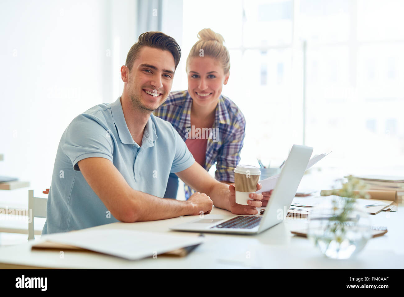 Young successful designers looking at camera at workplace during their ...