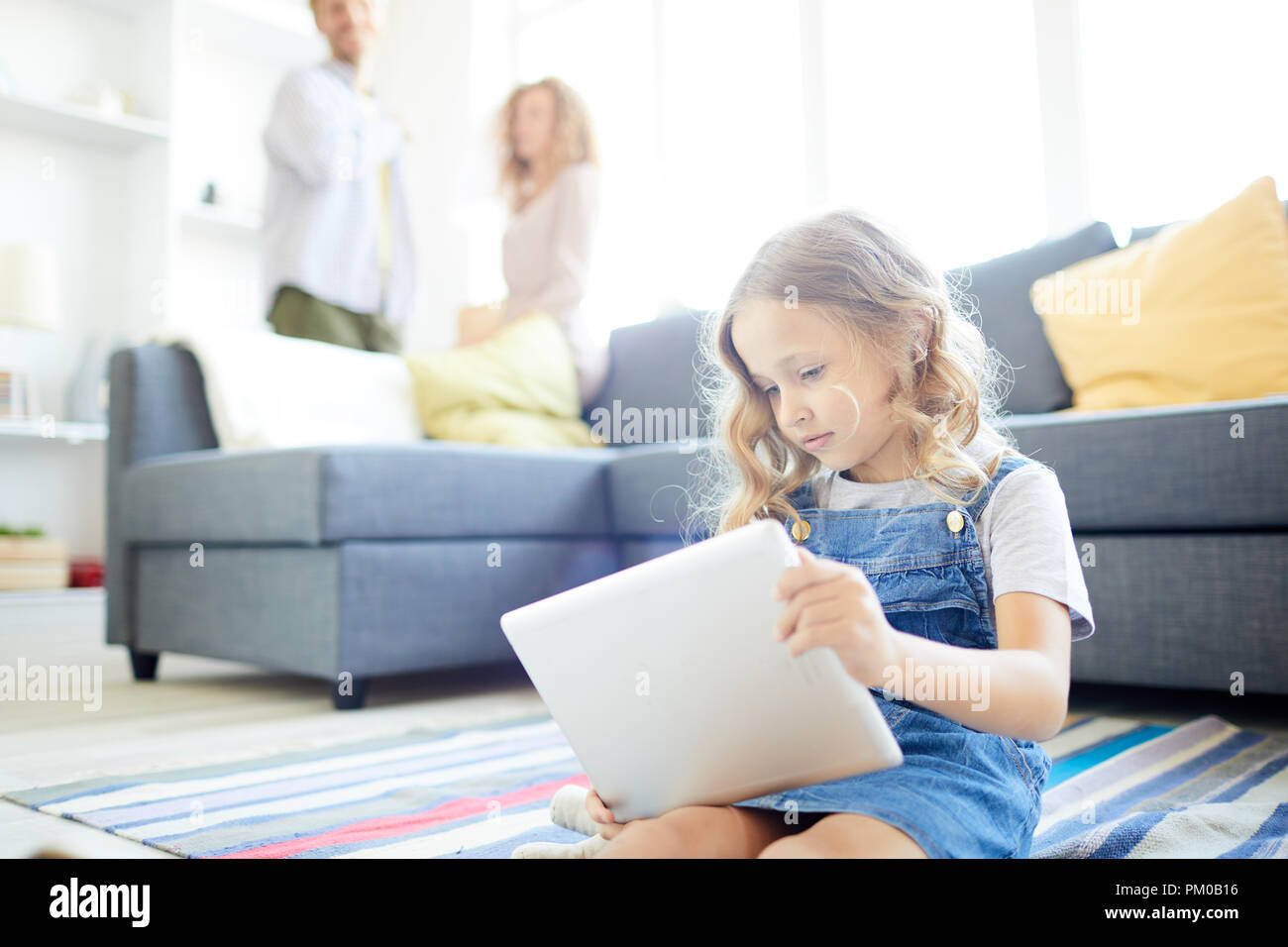 Little girl with touchpad sitting on the floor of living room and ...