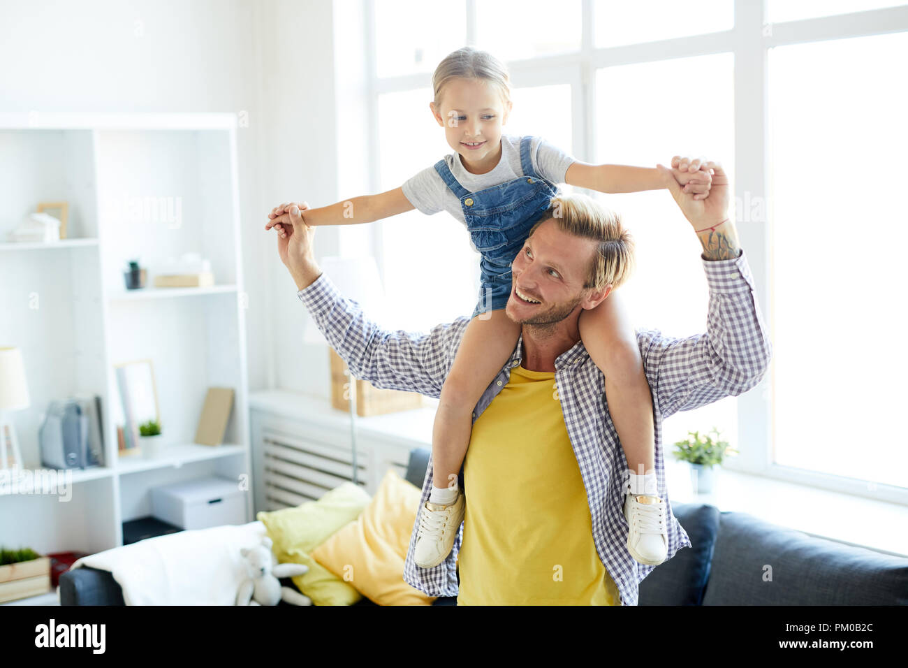 Happy dad holding his little daughter by hands while keeping her on his ...