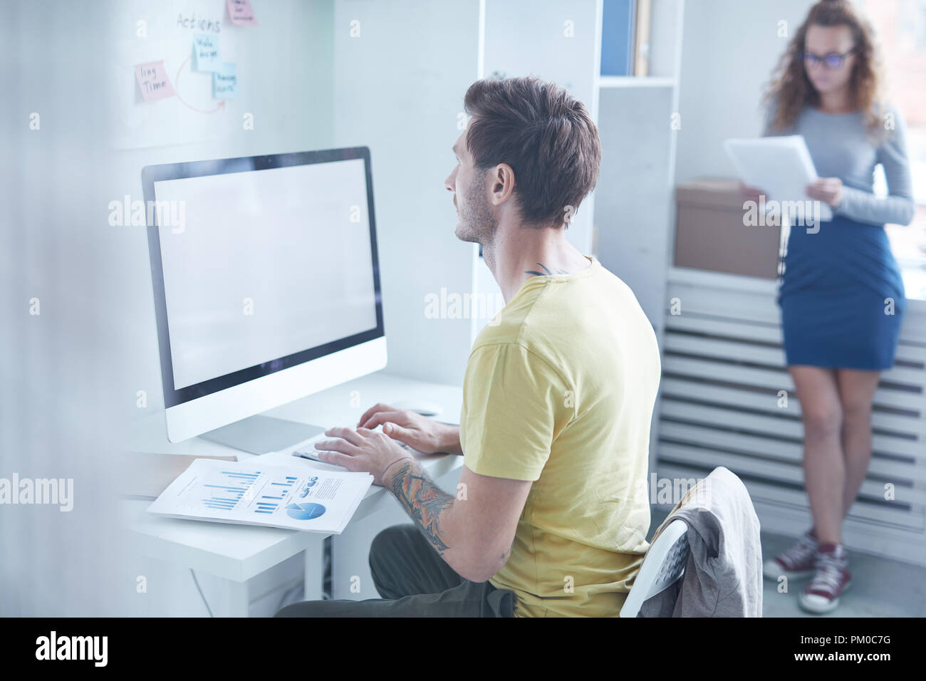 Young designer working in front of computer monitor by desk with his ...