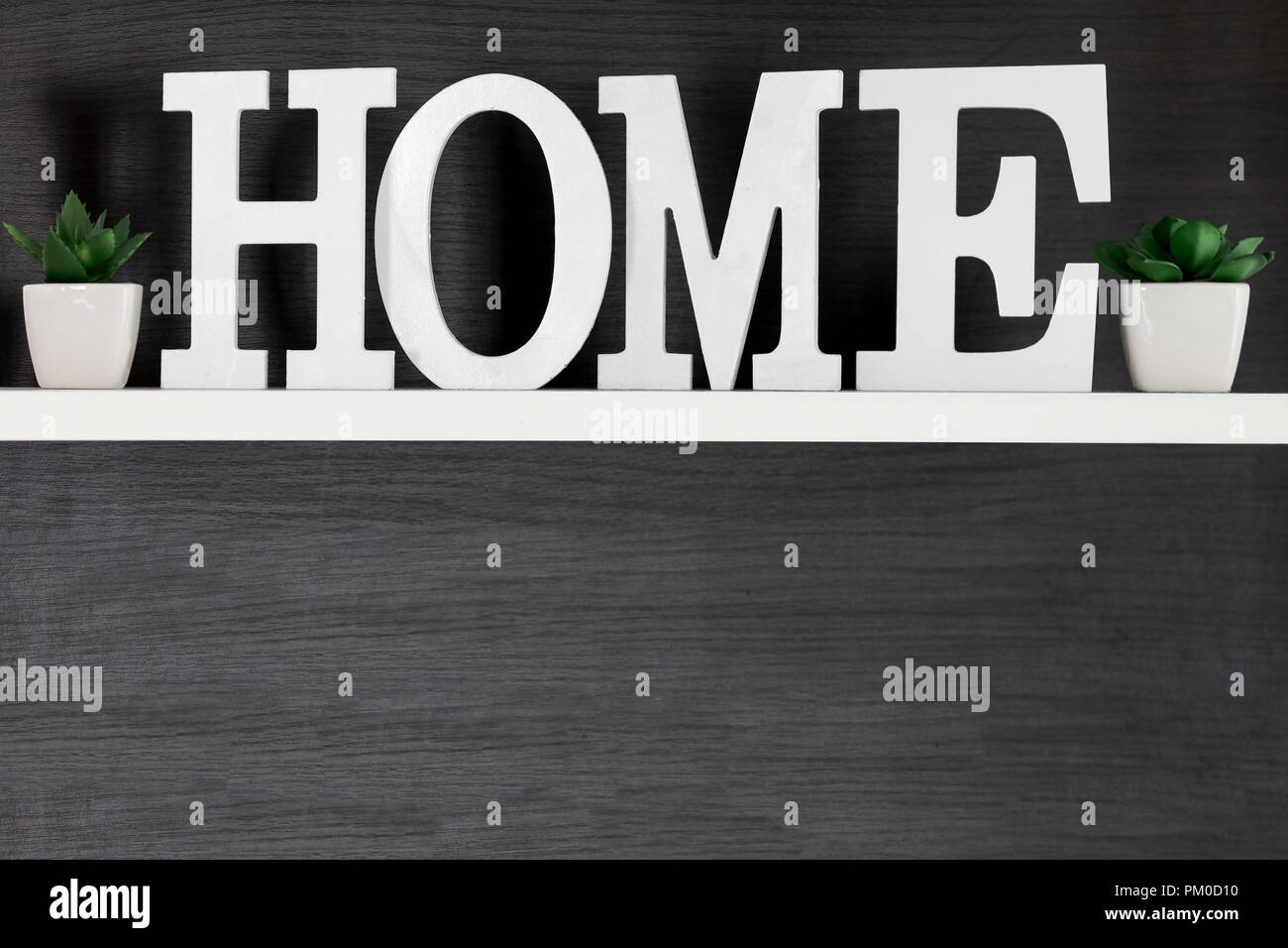 Home letters decor on white shelf with dark wood background, copy space ...