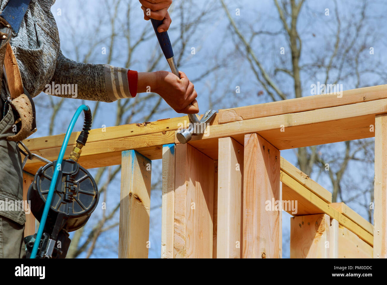 Authentic construction worker framing building contractor using nail ...