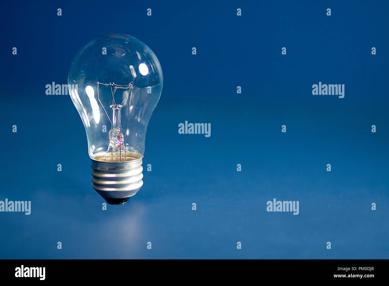 Light bulb standing by itself on blue background Stock Photo - Alamy