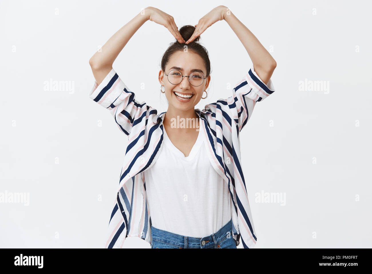 Love you. Indoor shot of happy and funny cute woman in glasses and bun ...