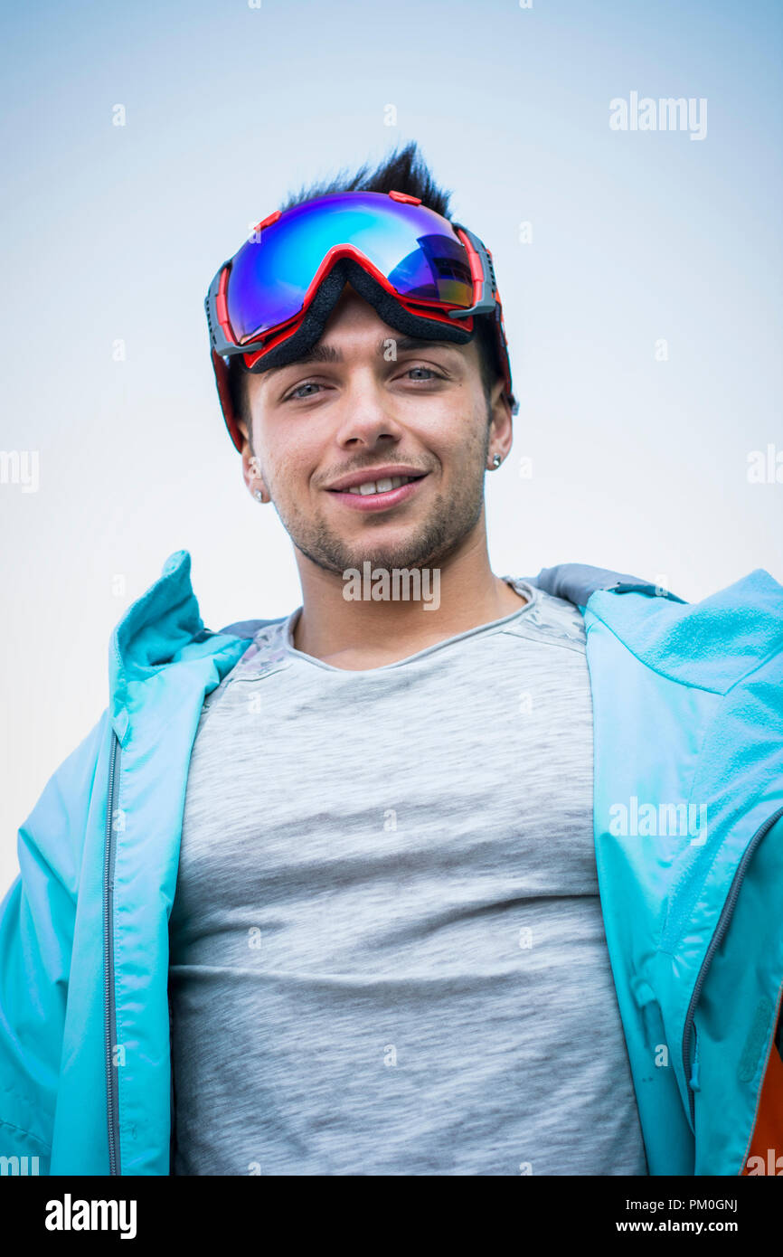 Friendly attractive skier or snowboarder against blue sky looking at ...