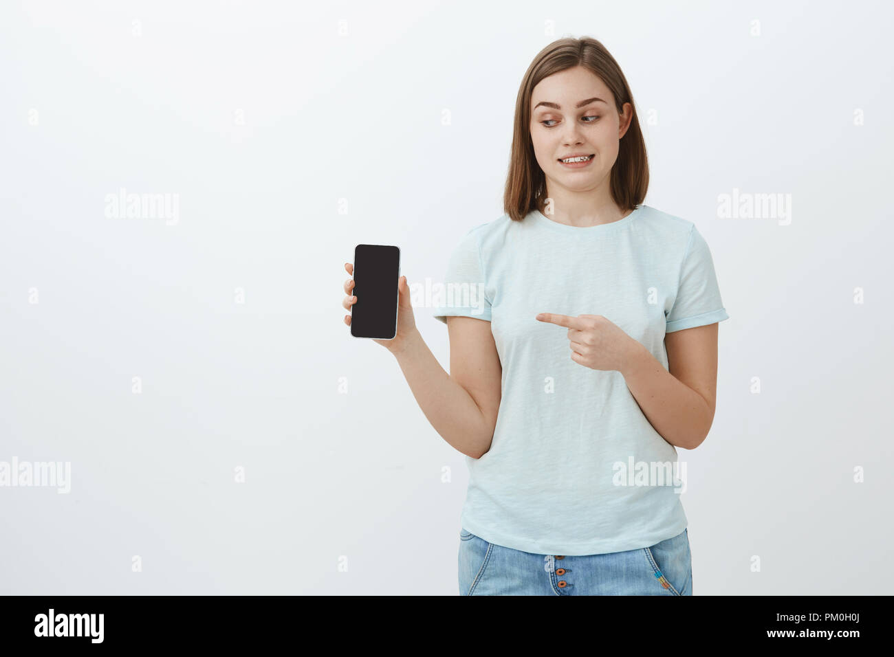 Studio shot of awkward cute female student in trendy t-shirt and jeans ...