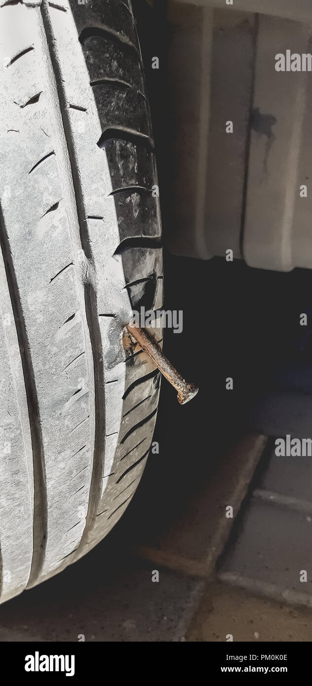 long large nail struck the wheel of the car Stock Photo - Alamy