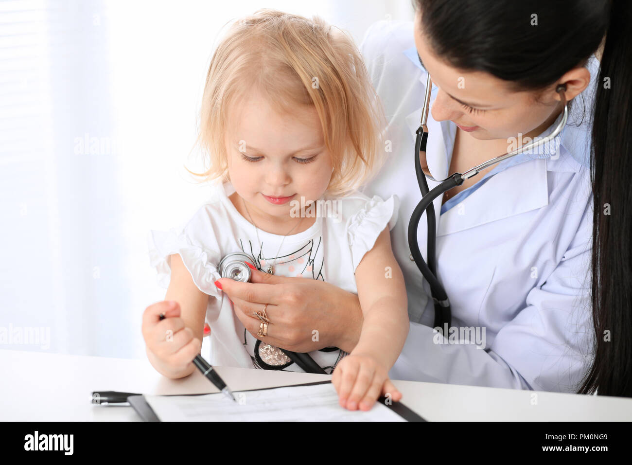 Doctor and patient baby in hospital. Little girl is being examined by ...