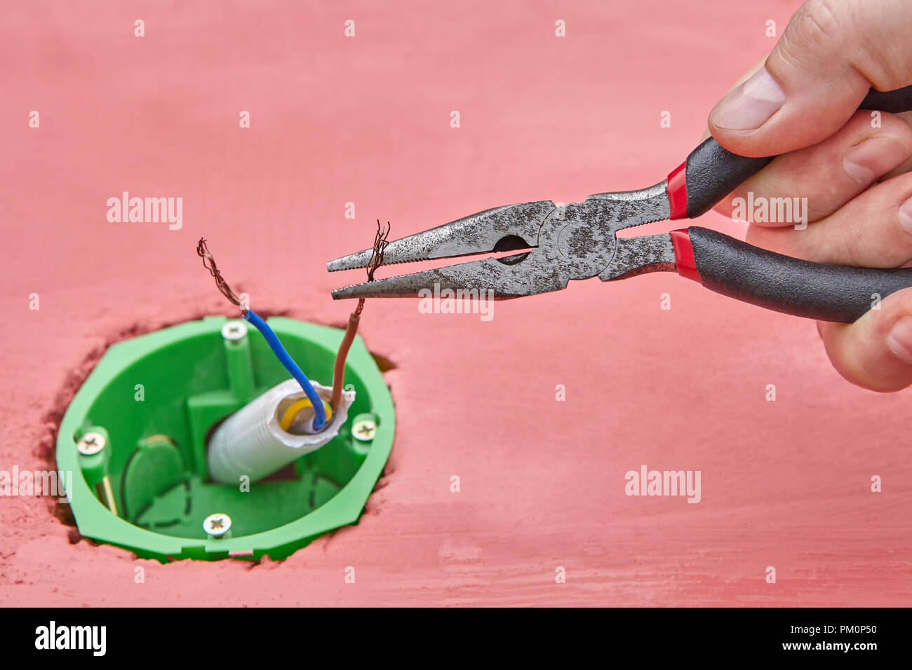 The electrician repairs the wiring using pliers, hand with the tool ...