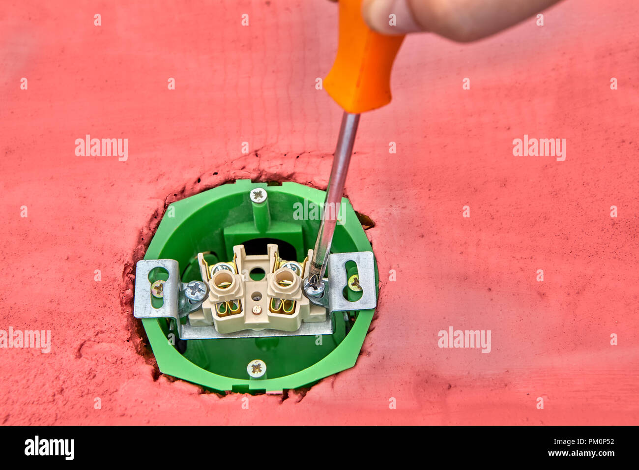 Installation of an electrical outlet in socket on pink wall Stock Photo ...