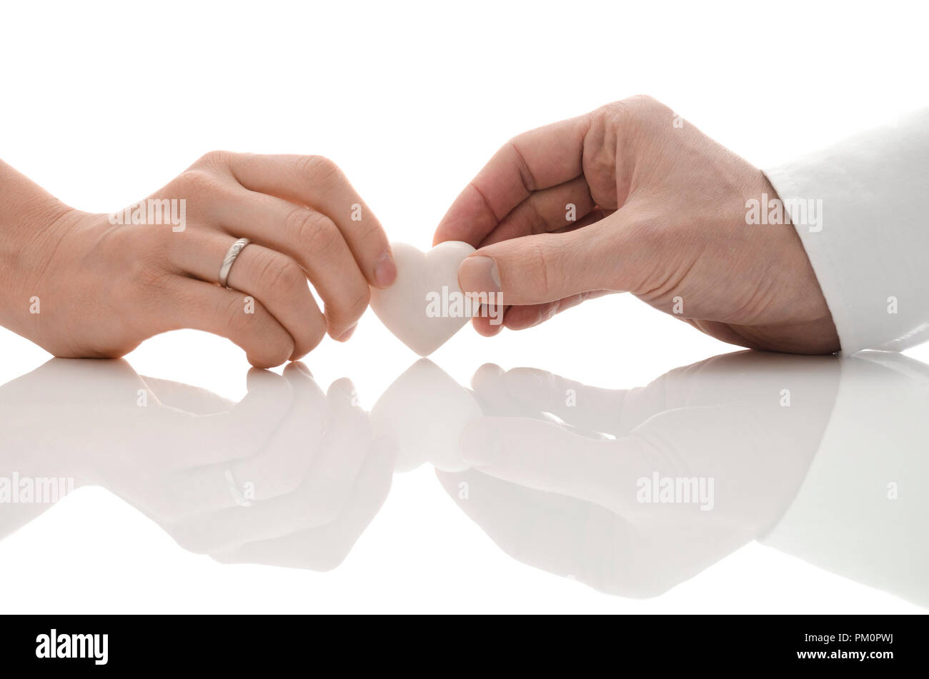 Couple sharing one heart over white table. A beautiful love concept ...