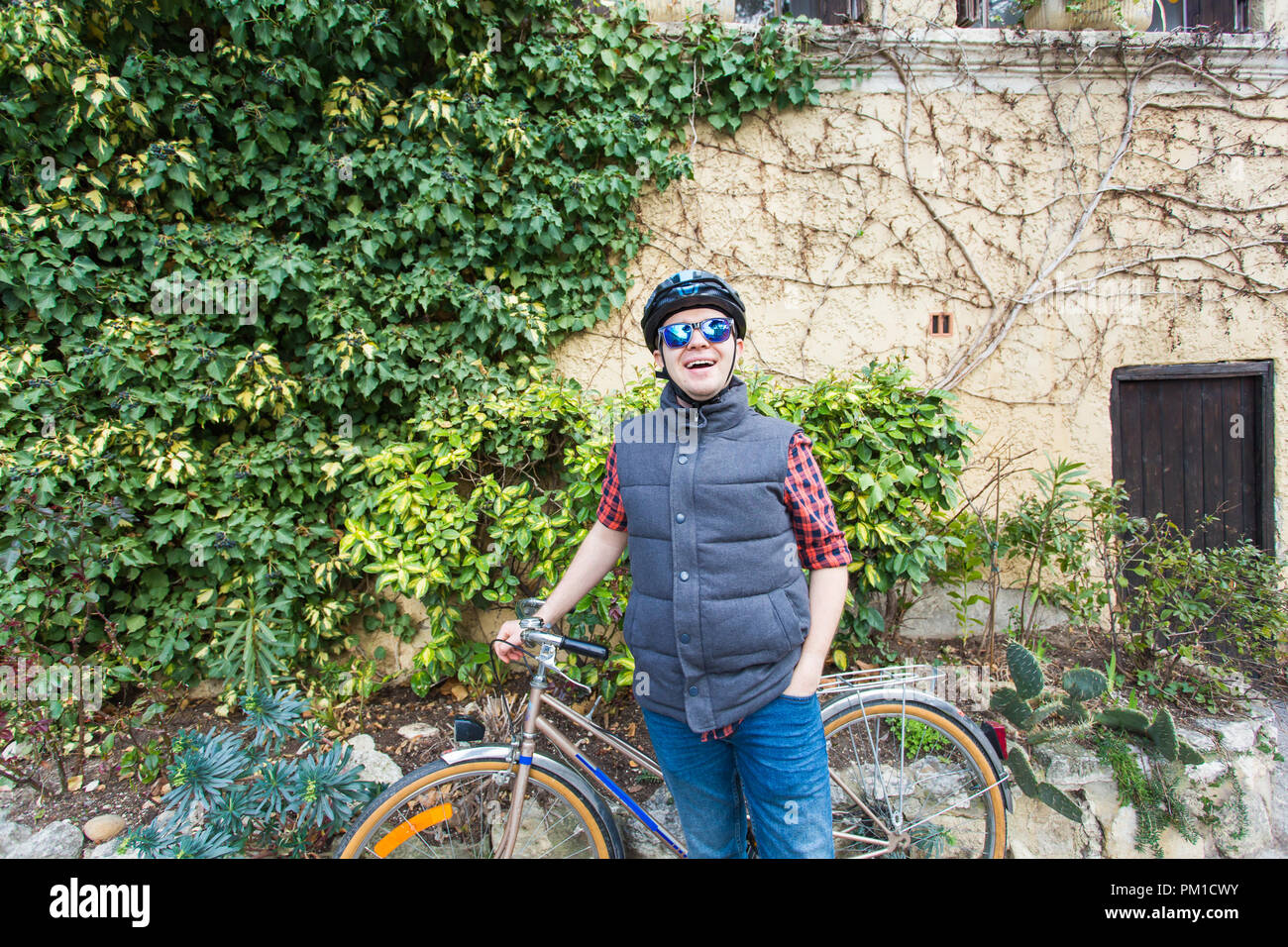Handsome guy cyclist in cycling clothes and helmet posing near bicycle ...