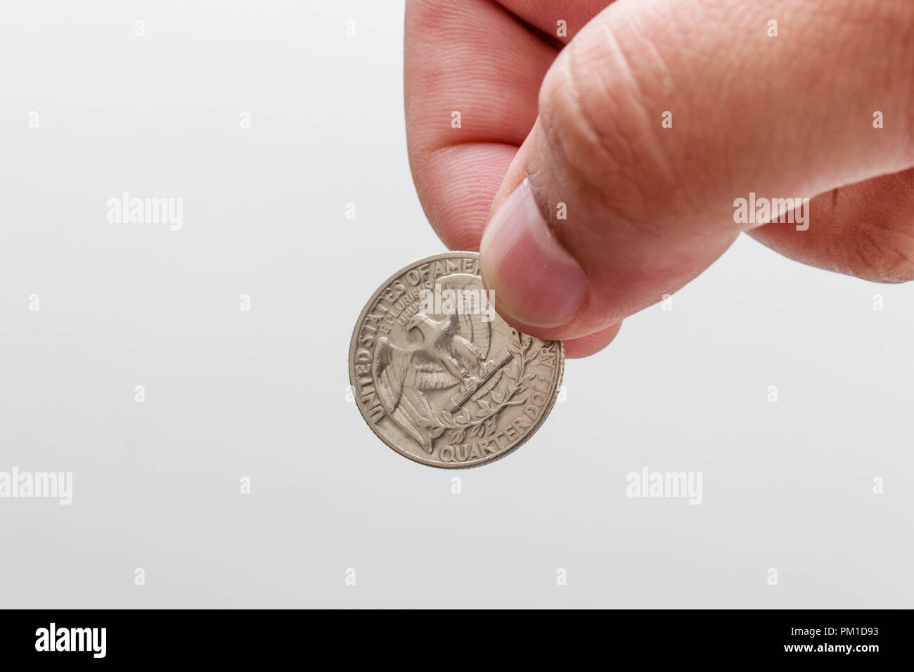 Male hand holding quarter dollar coin, white background Stock Photo - Alamy