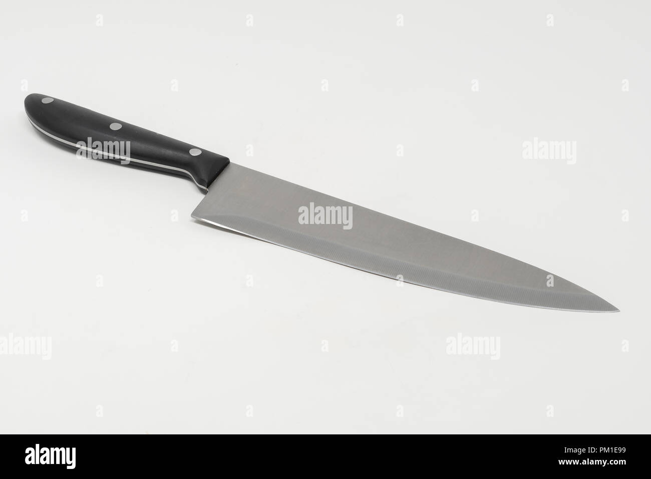 An angled stainless steel kitchen knife set against a white background ...