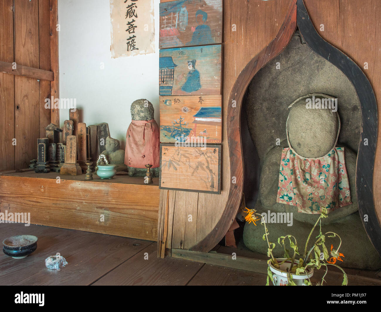 Statue of faceless god with dead flowers, altar with sacred statues and ...