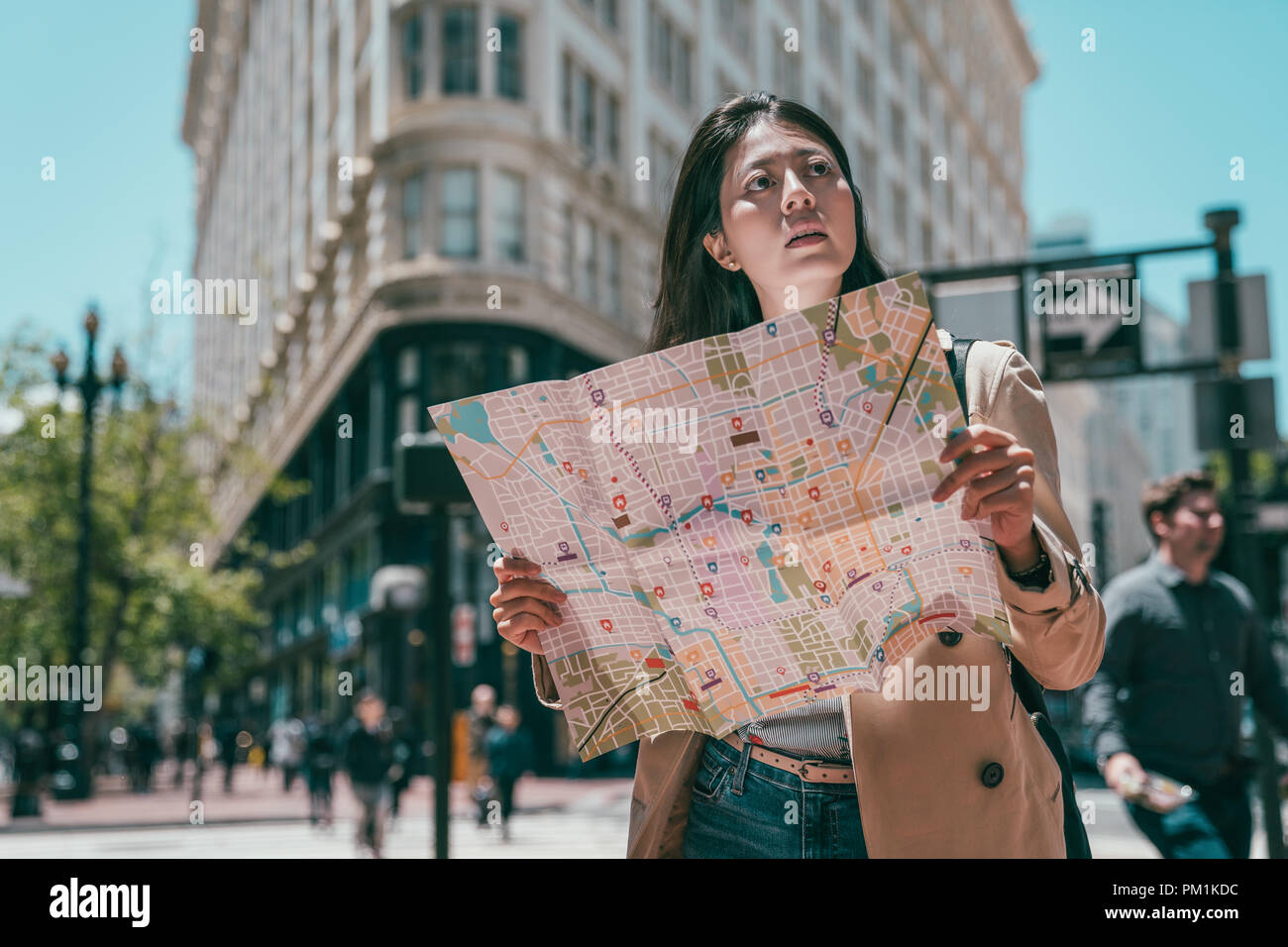 pretty young female holding a guide map and looking lost in the middle ...