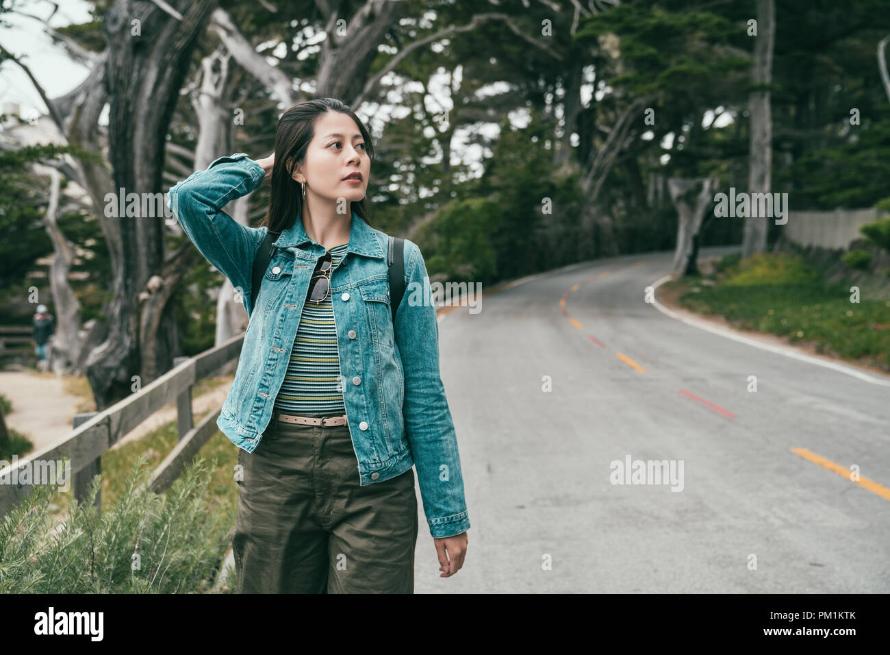 beautiful young woman looking around curiously while walking down along ...