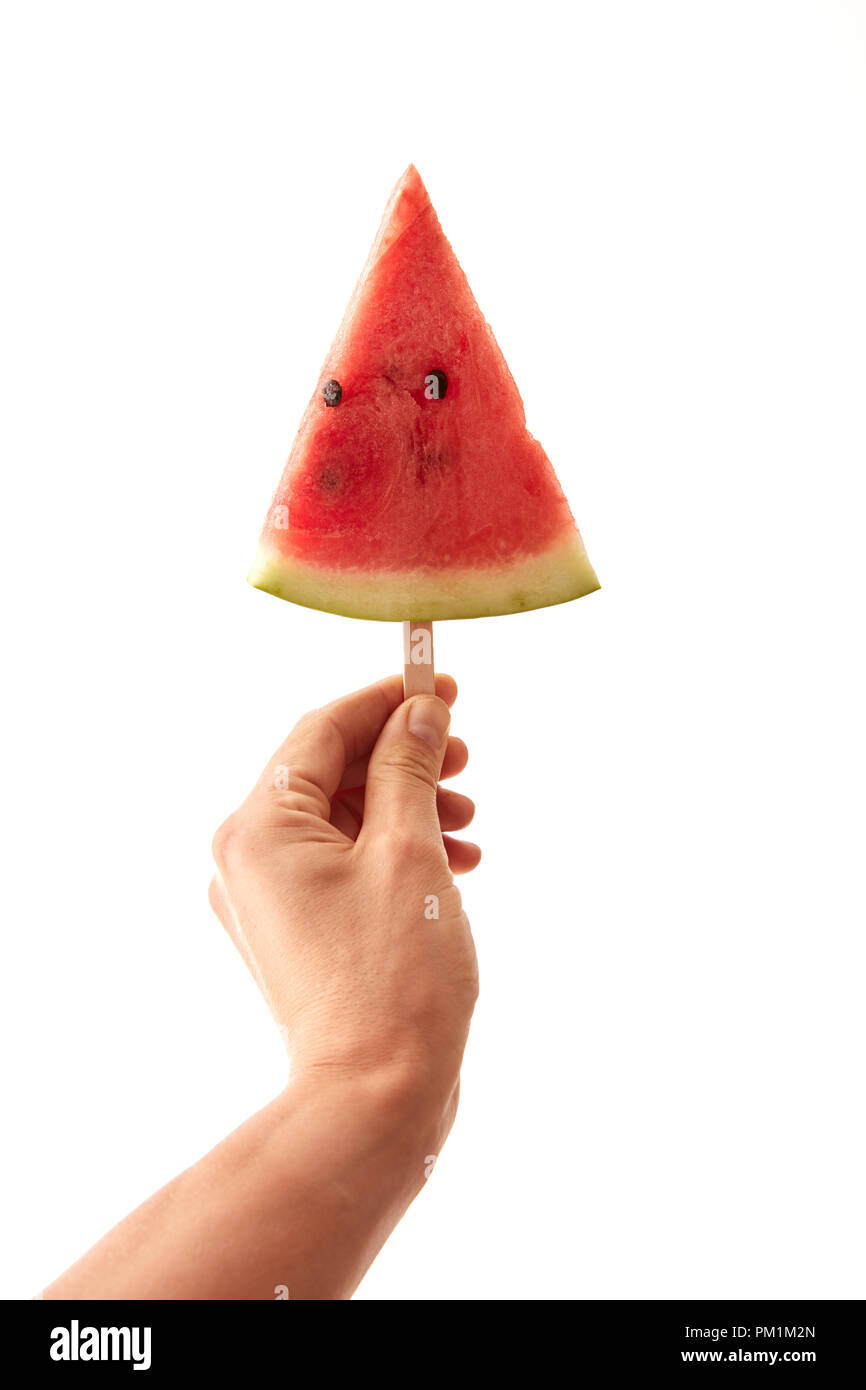 A man's hand holds a juicy piece of watermelon lolly on a white ...
