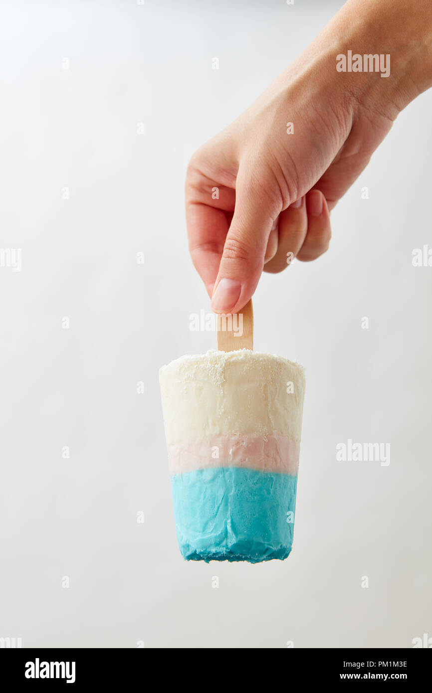 Ice lolly. A girl's hand holds a homemade sweet ice cream on a gray ...