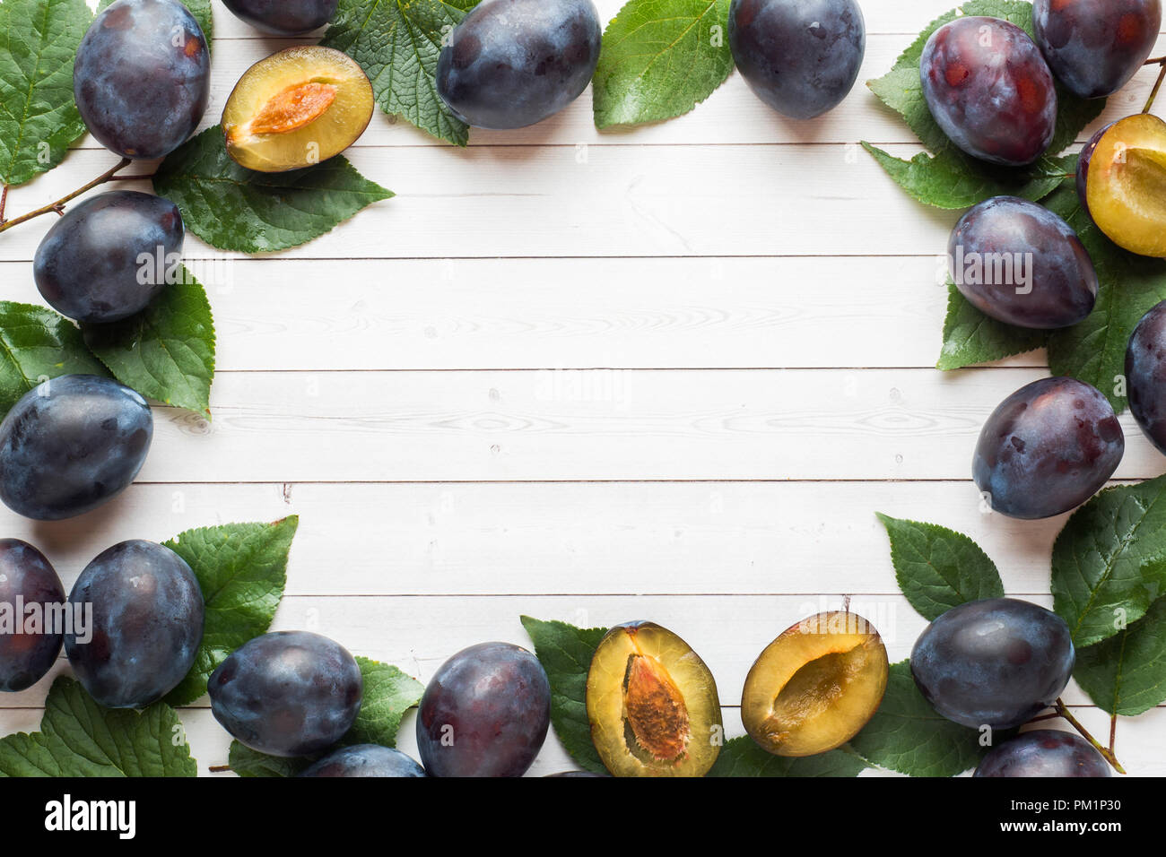 Fresh plum fruit with leaves on a light table Stock Photo - Alamy