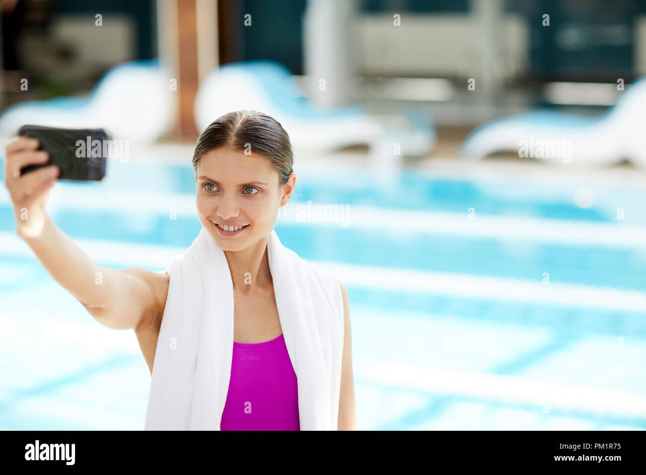 Young modern woman with soft towel on shoulders making selfie by ...