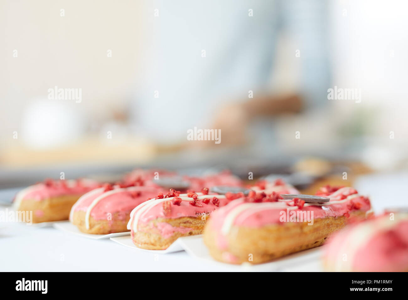 Row of yummy fresh pastry with pink glaze and sprinkles in display of ...