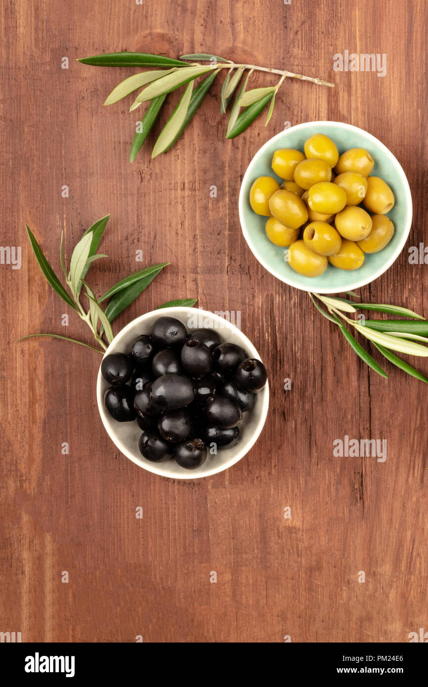 An overhead photo of various olives in bowls with leaves and a place ...
